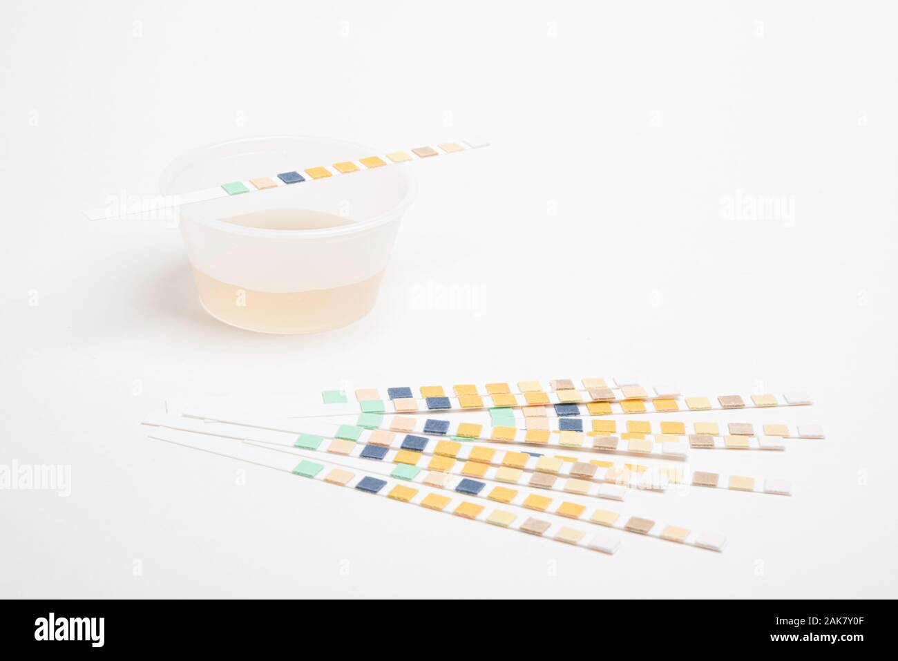 Several unused reagent test strips with a urine specimen set on plain ...