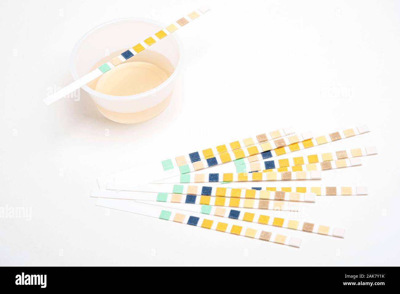 Several unused reagent test strips with a urine specimen set on plain ...