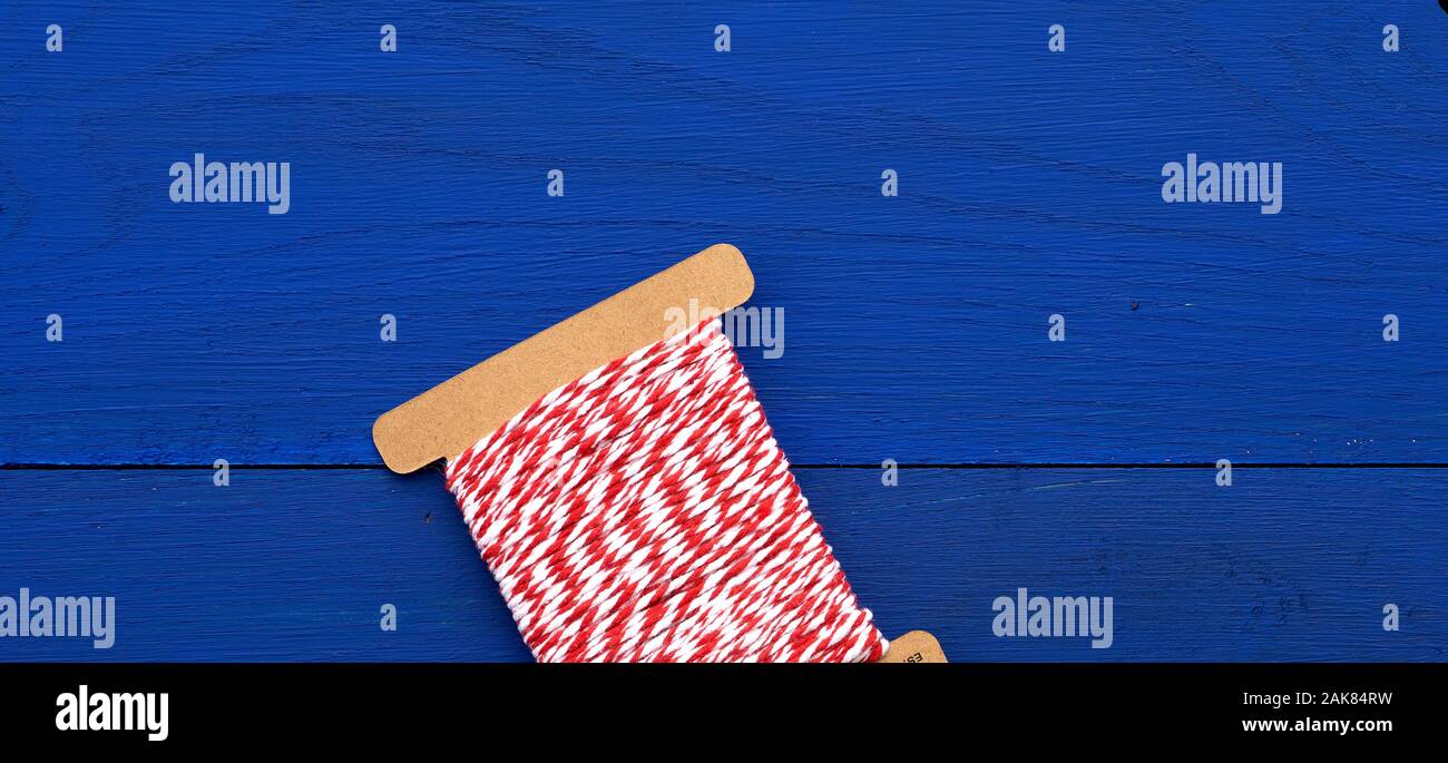 skein of craft red-white thread on a blue wooden background, backdrop ...