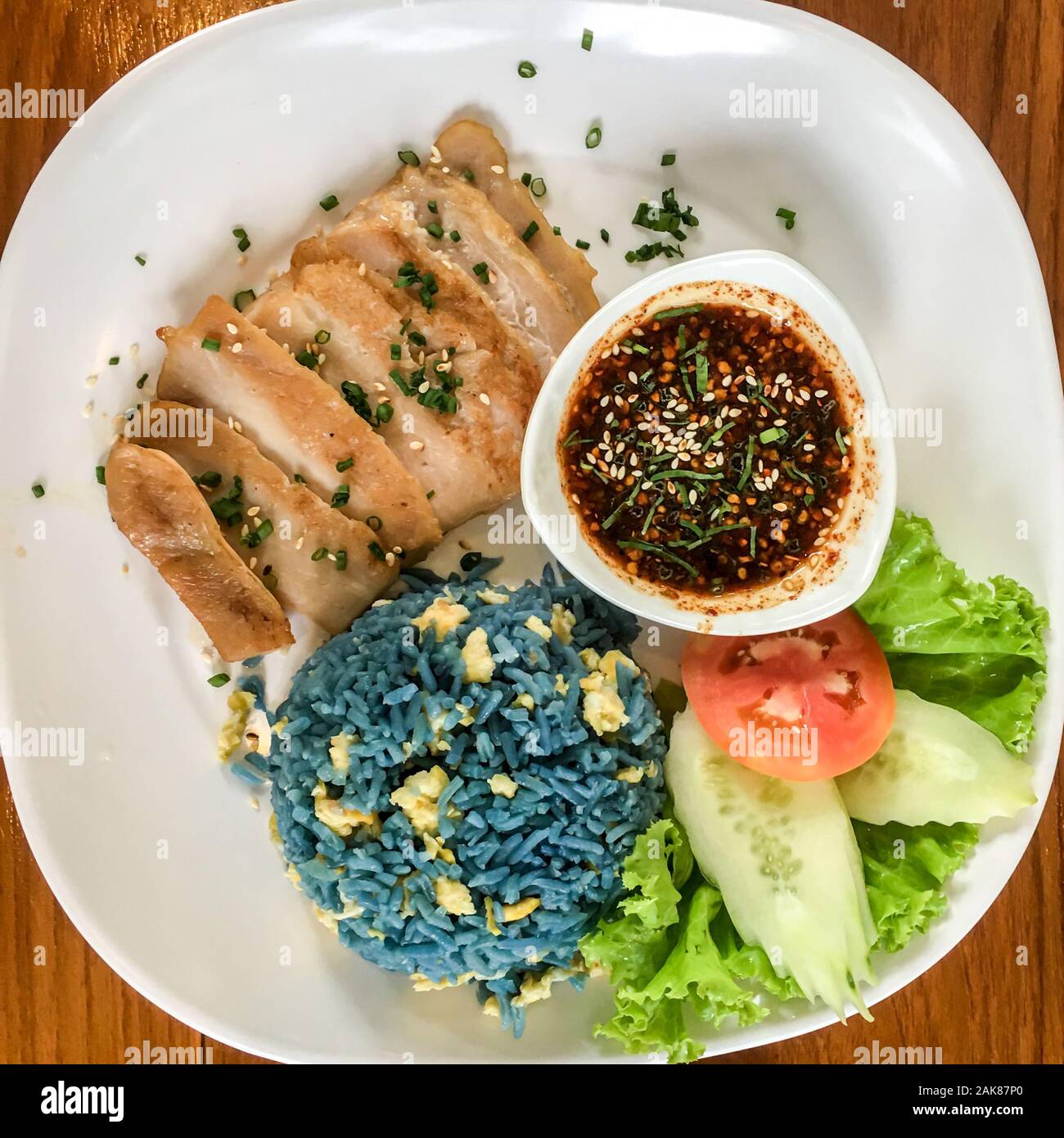 fried blue rice with griled pork and cucumber slice on a plate. Thai ...
