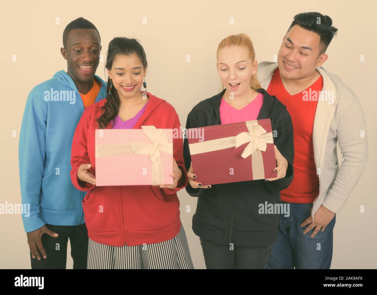 Happy diverse group of multi ethnic friends smiling while opening gift ...