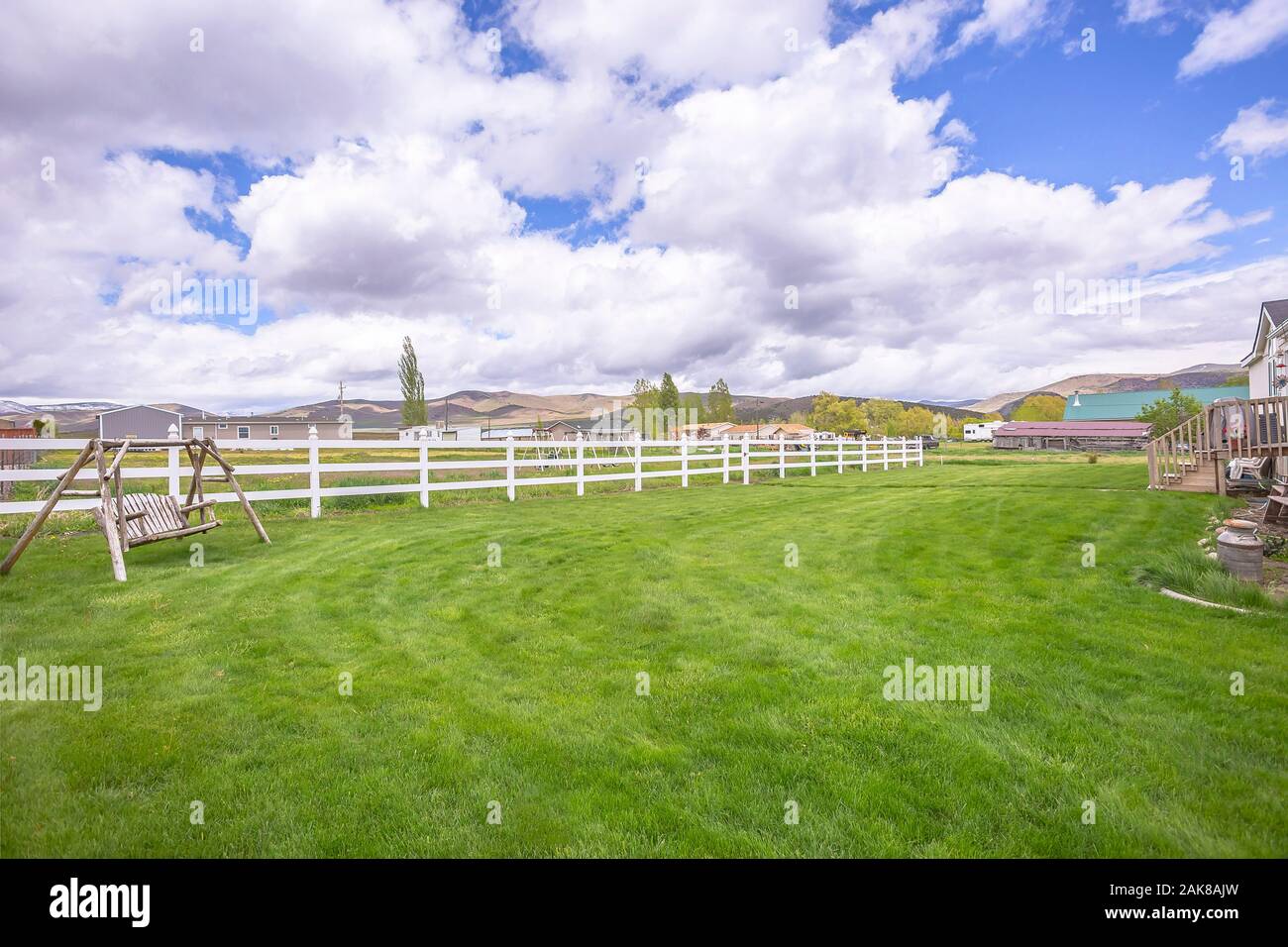Spacious yard of a home with garden swing lush green grasses and white ...