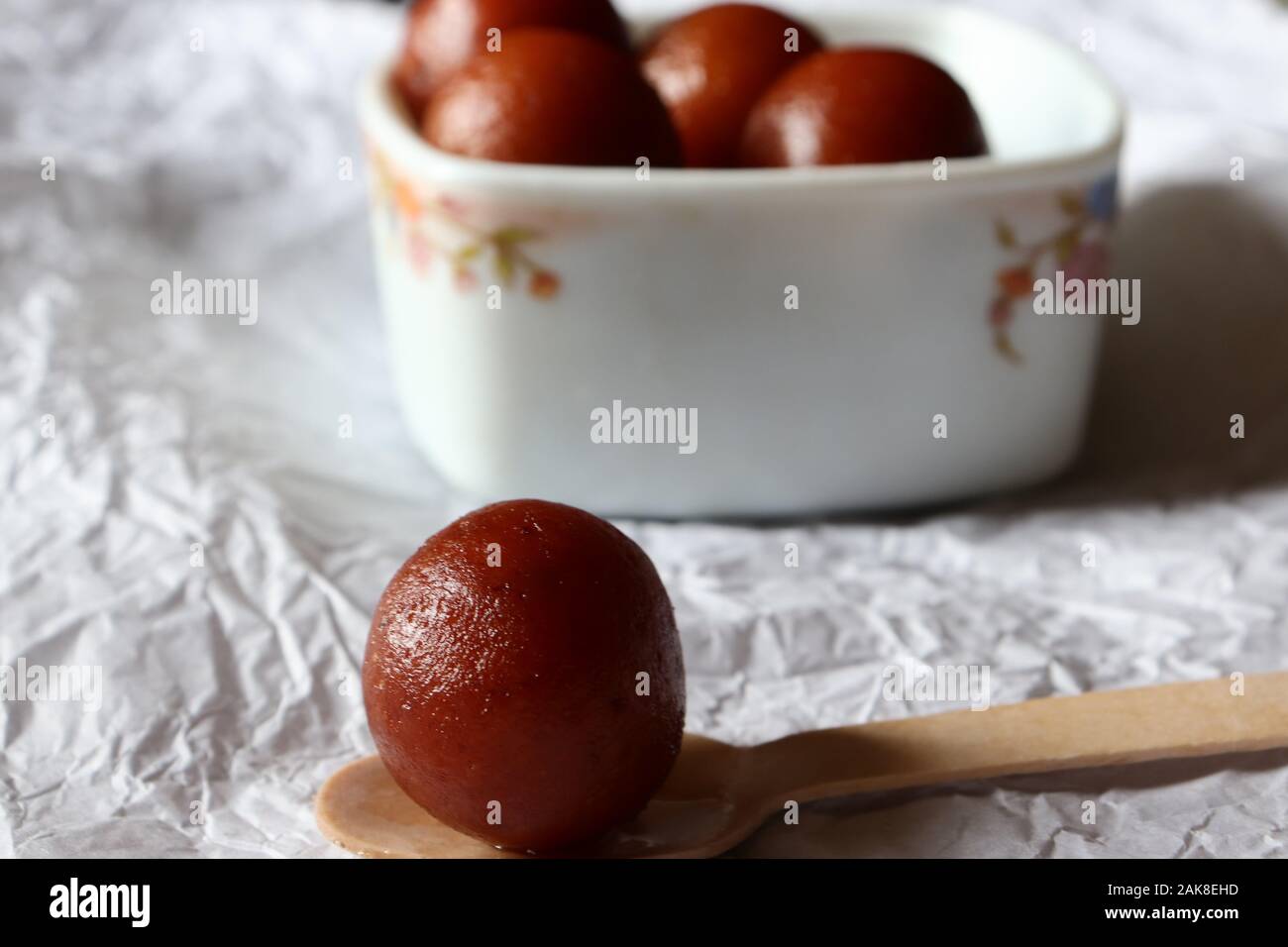 Close-up of a single gulab jamun in a bamboo spoon/Indian sweet Stock ...