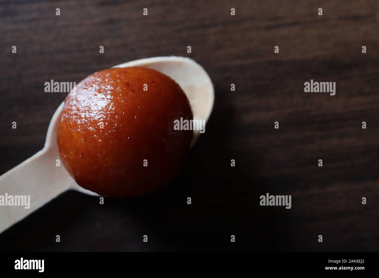 Close-up of a single gulab jamun in a bamboo spoon/Indian sweet Stock ...