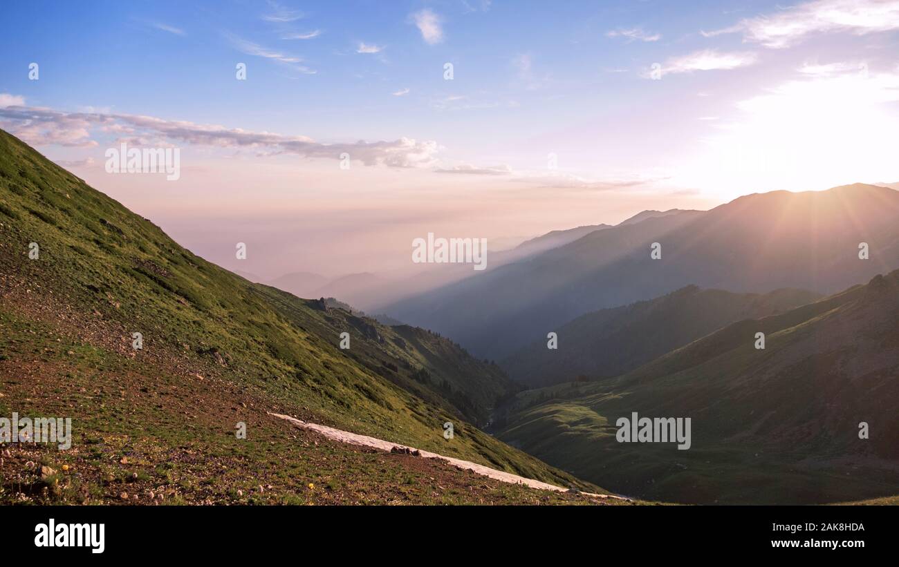 Rising sun with its rays illuminates a mountain gorge; spring warmth, a ...
