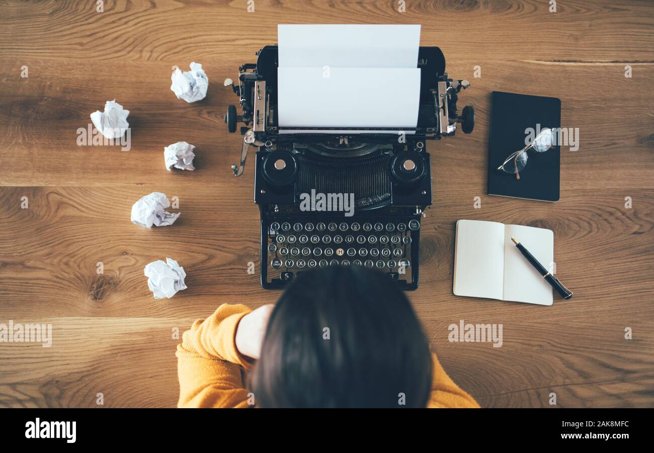 Top view of writer above typewriter and crumpled papers around ...