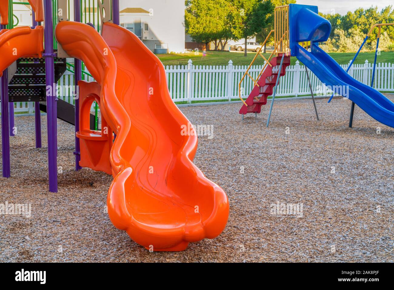 Close up of bright and shiny orange slide at a park with childrens ...