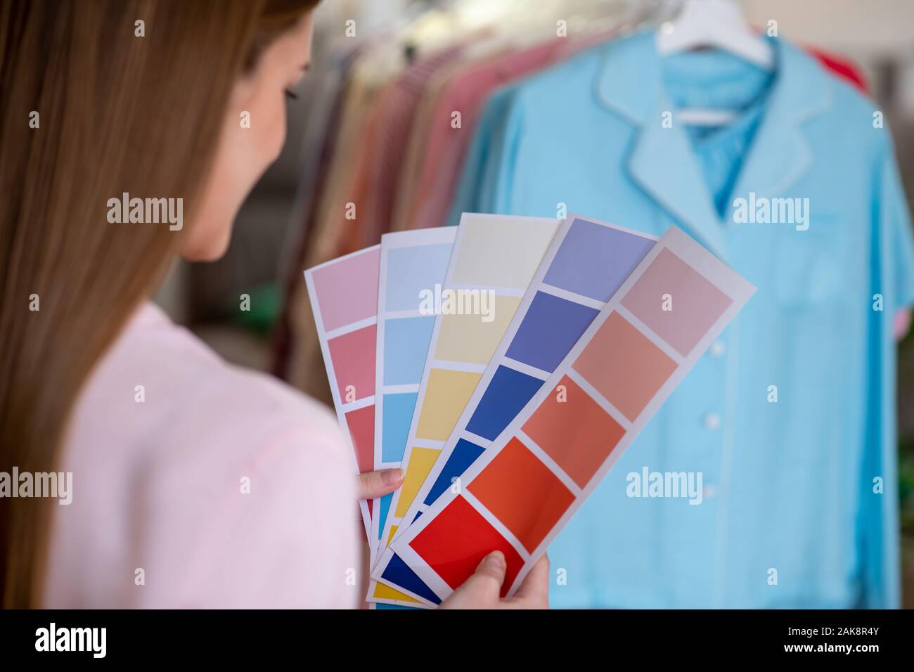Designer girl considering color combination with color scales in hands ...