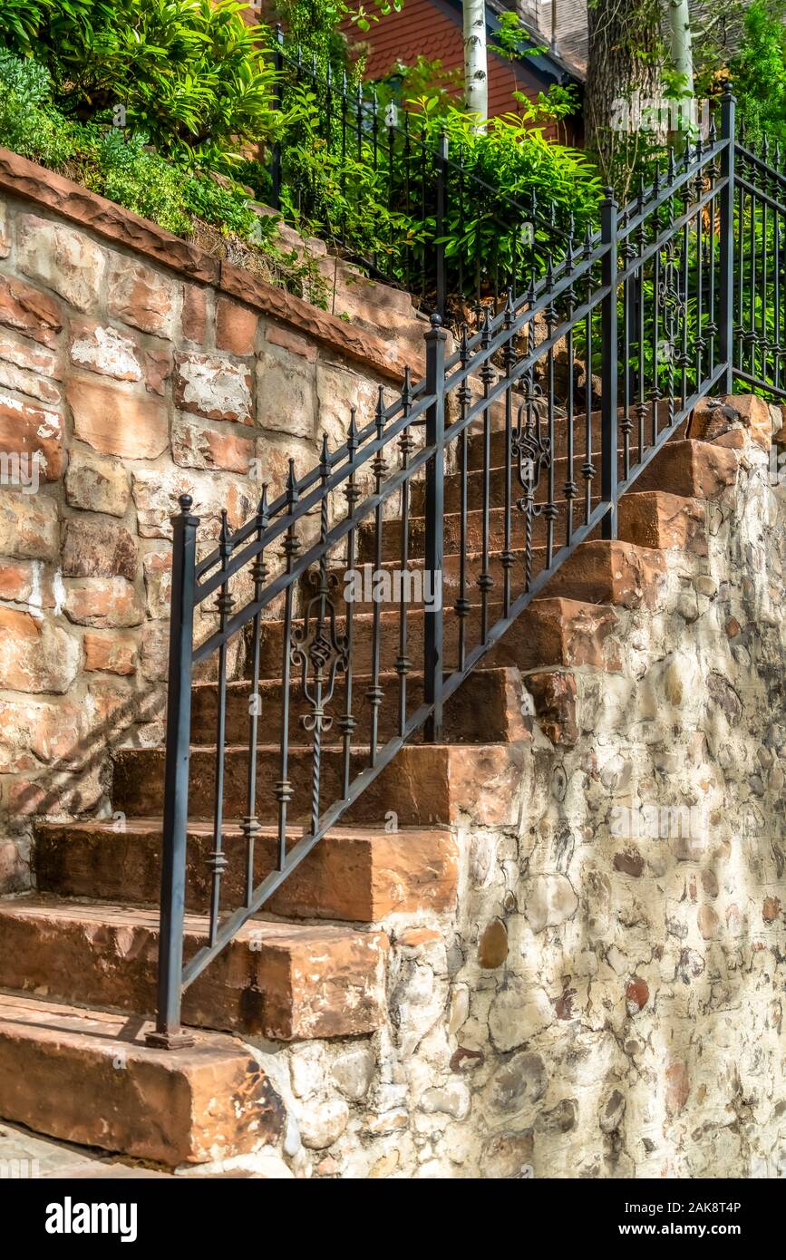 Outdoor staircase with stone steps and black metal railing against a ...