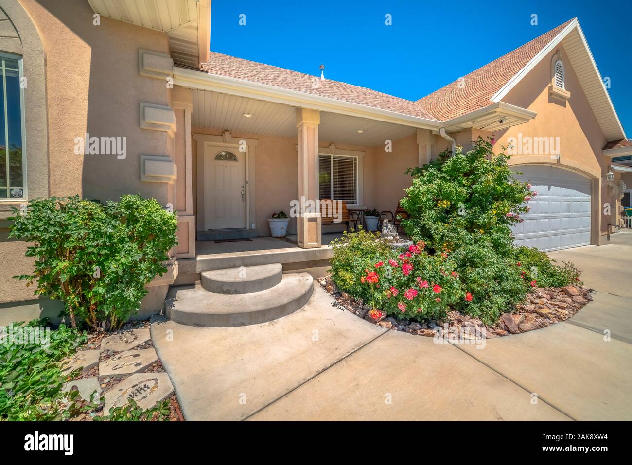 Pathway leading to garage and stairs of a home with porch and ...