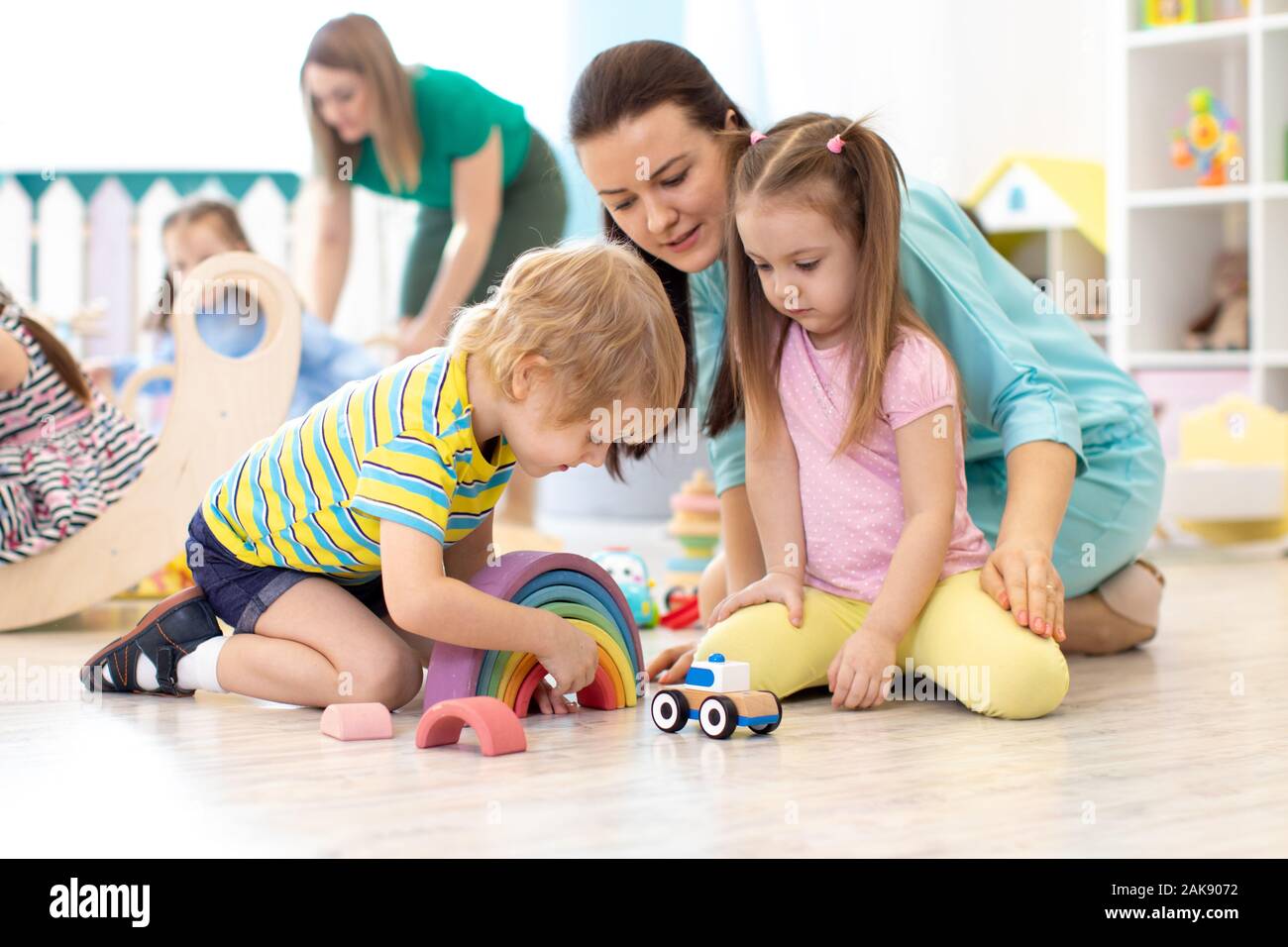 Preschool kids play with building bricks in while sitting on floor in ...