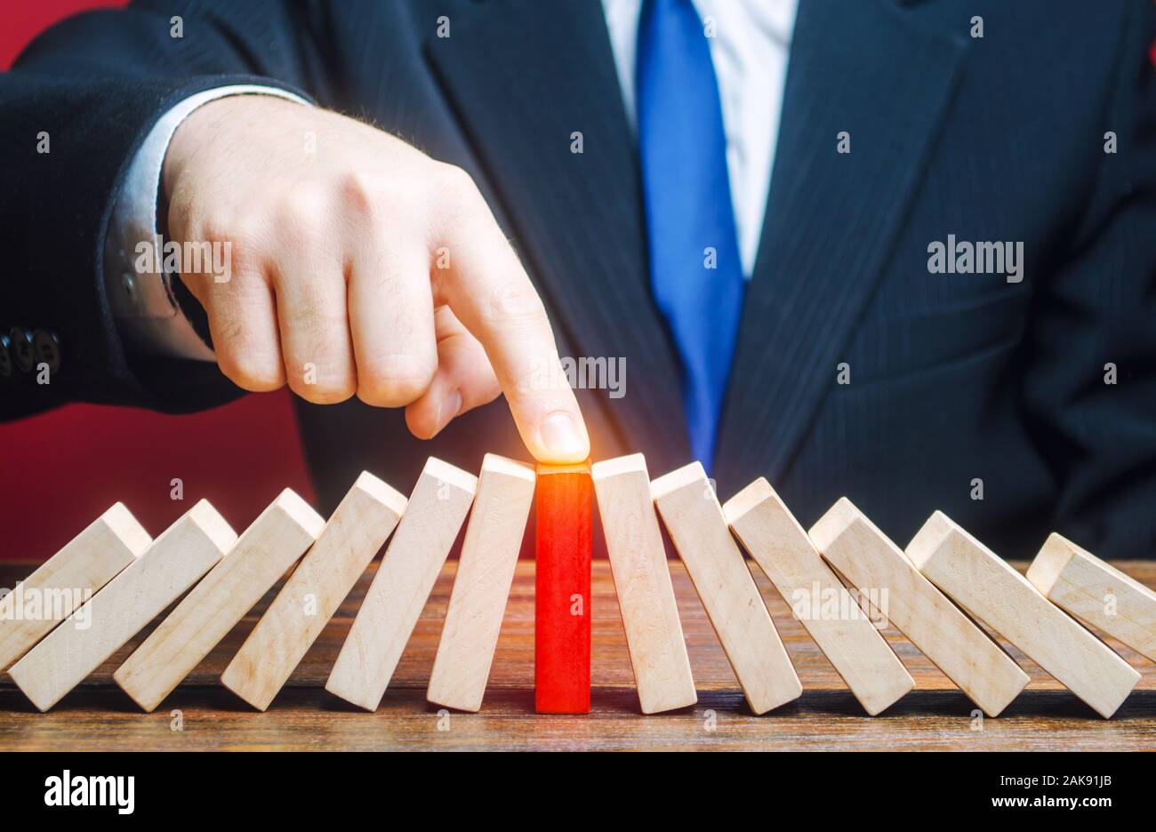 Businessman with a touch stops process of falling dominoes. Risk ...