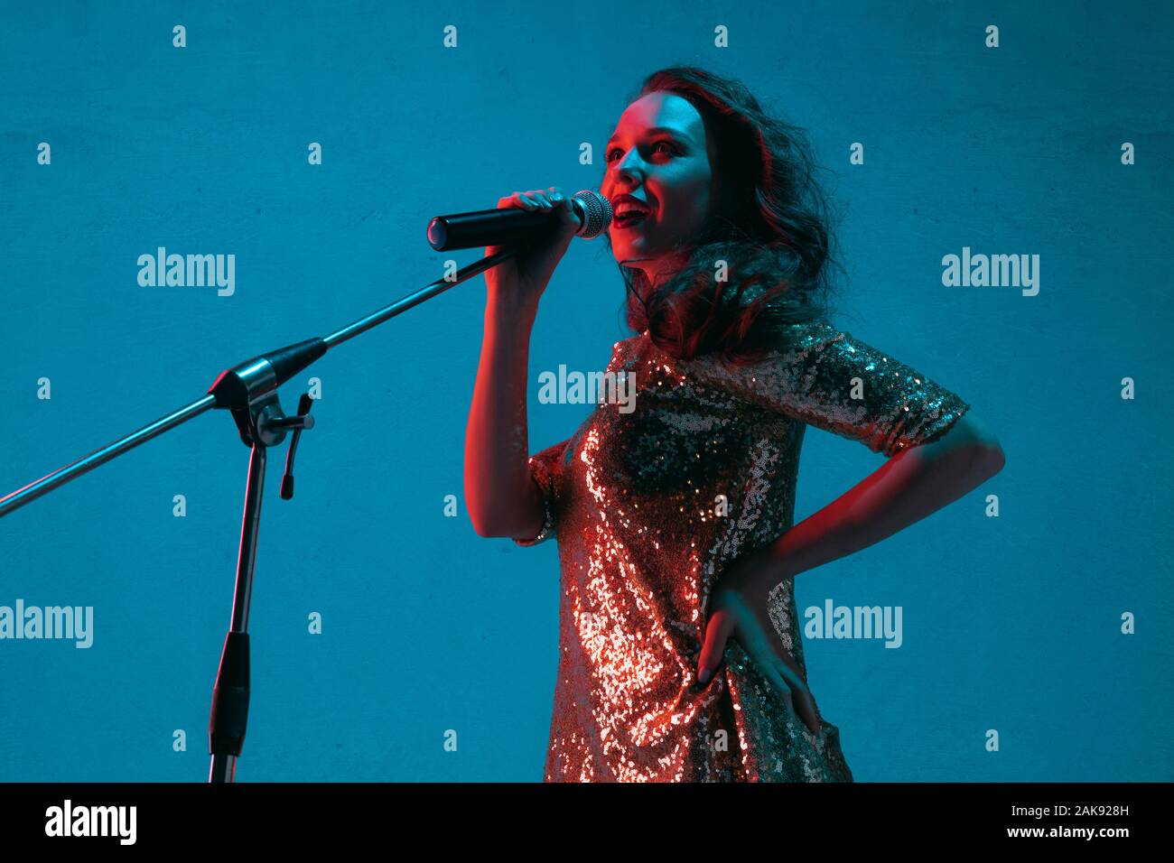 Caucasian female singer portrait isolated on blue studio background in ...