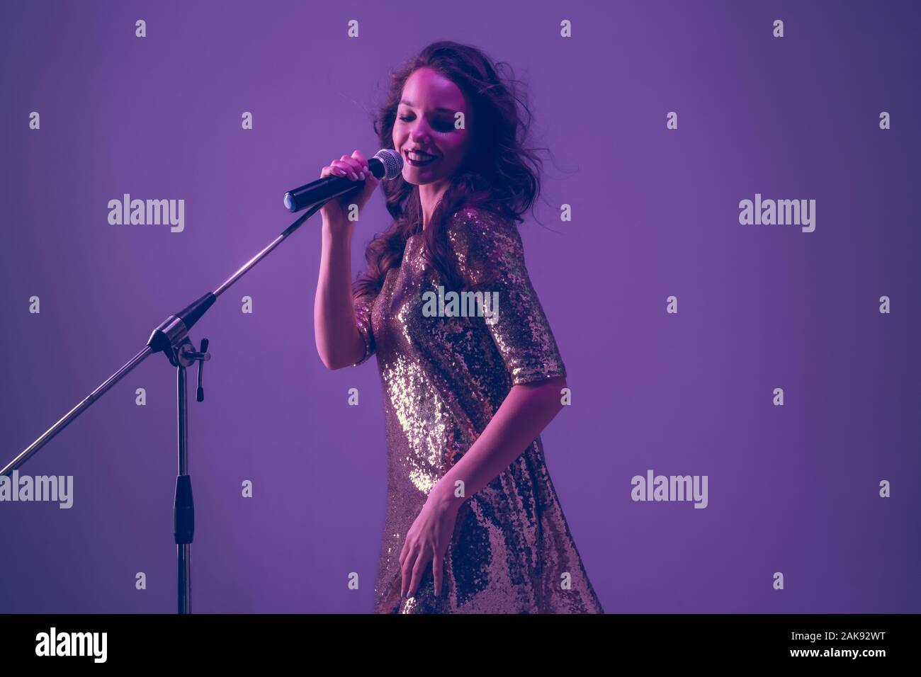 Caucasian female singer portrait isolated on purple studio background ...