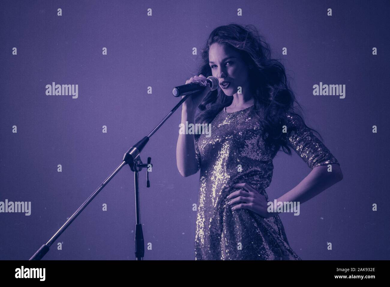 Caucasian female singer portrait isolated on purple studio background ...