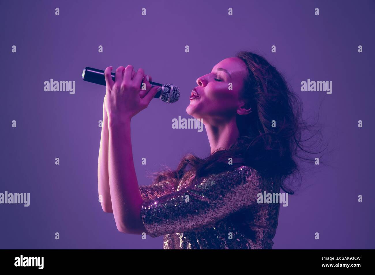 Caucasian female singer portrait isolated on purple studio background ...