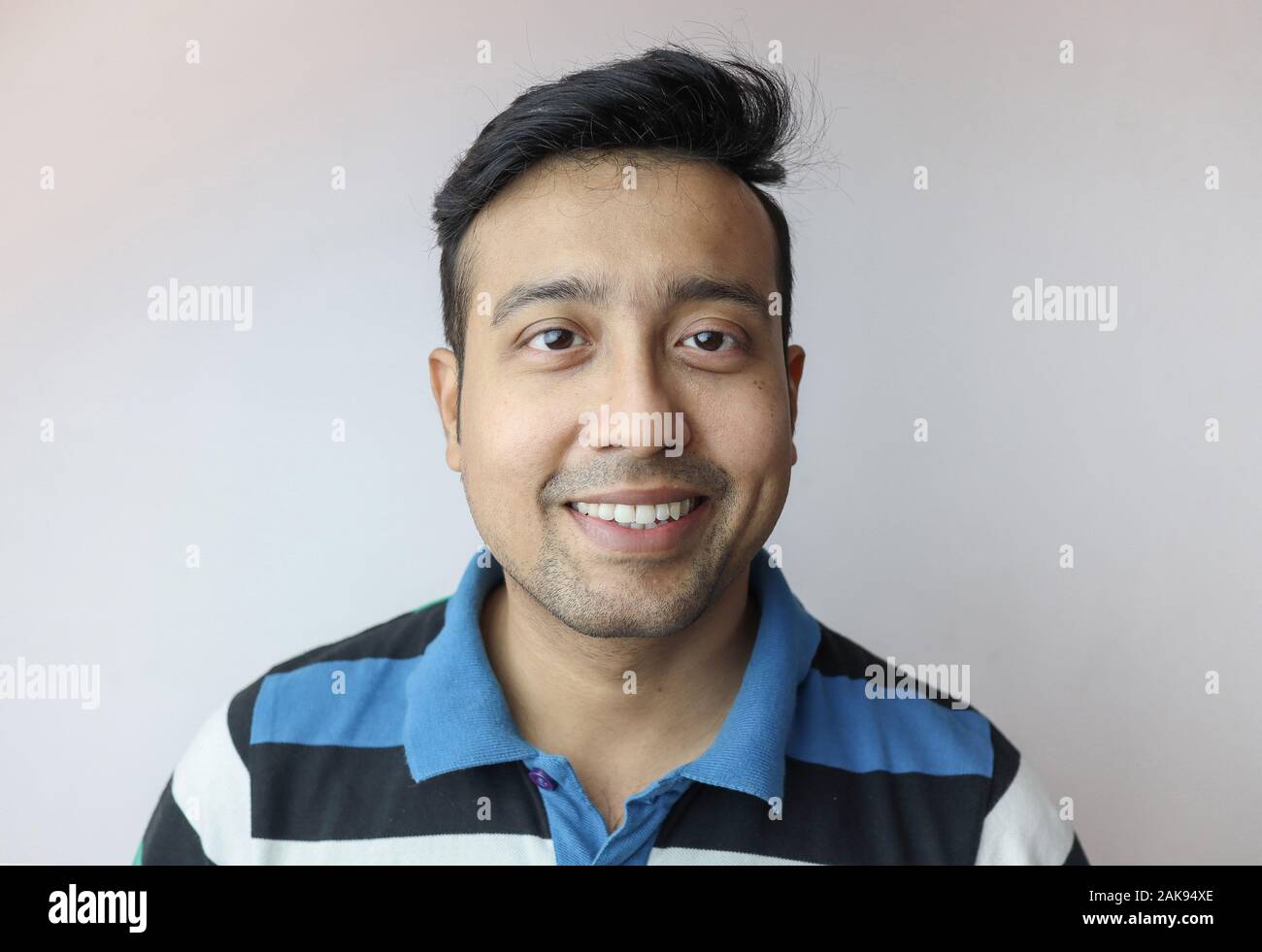 a young indian man confident and smiling isolated in white background ...