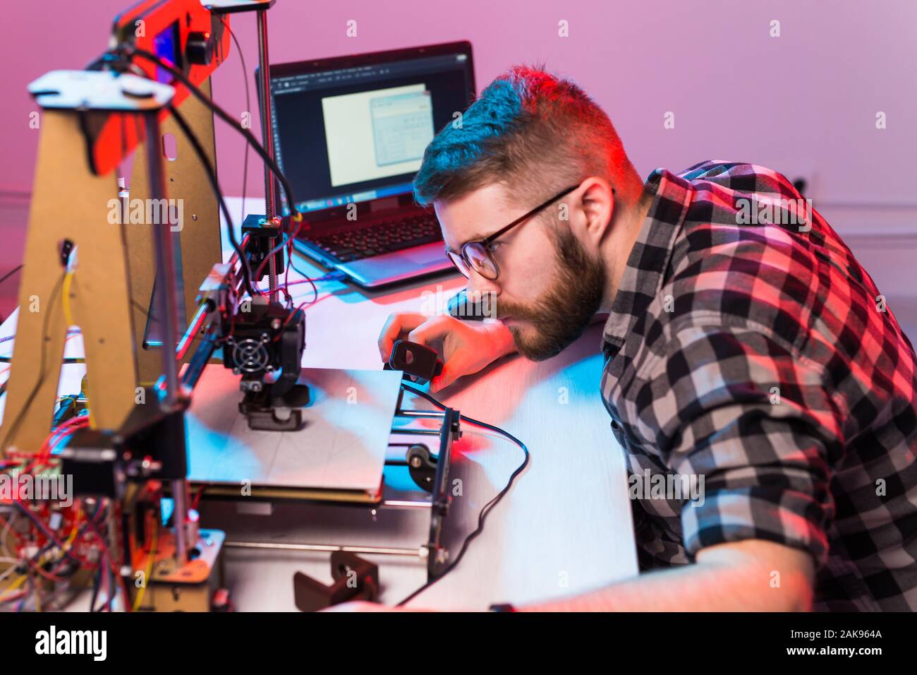 Young male designer engineer using a 3D printer in the laboratory and ...