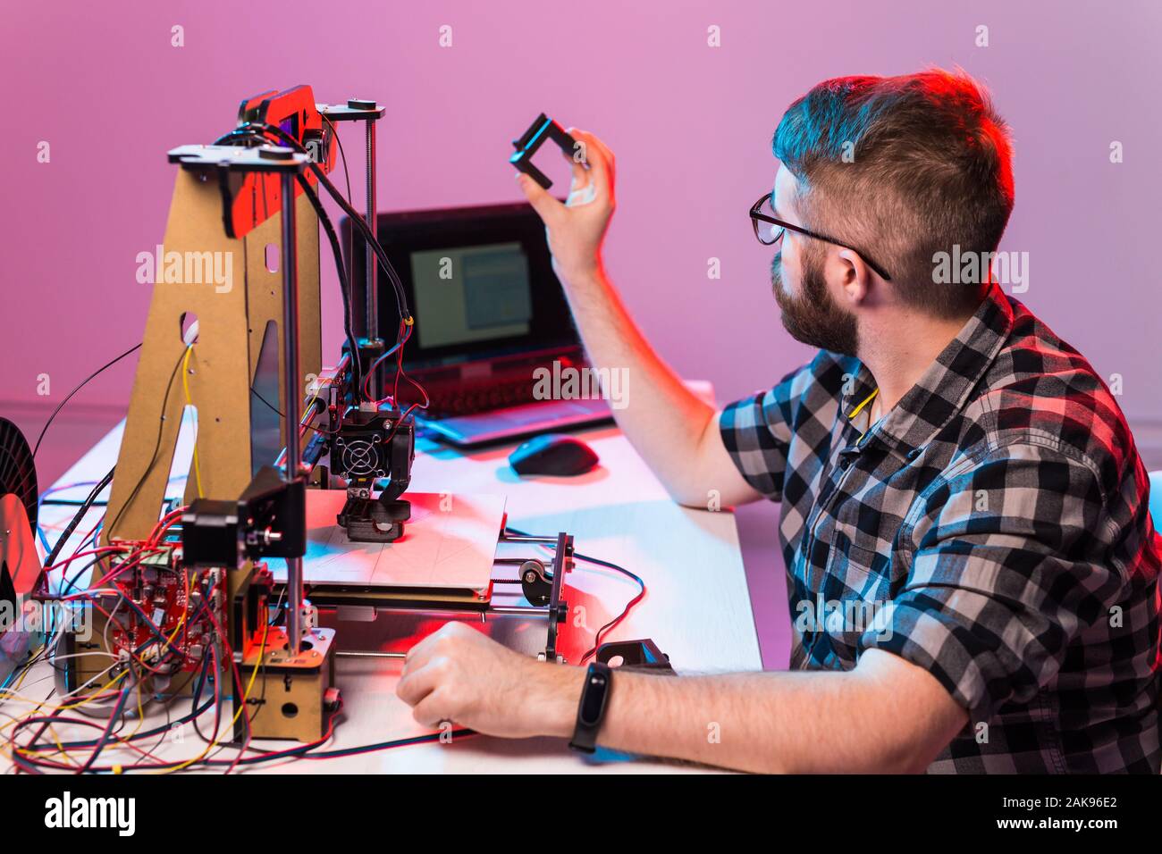 Young male designer engineer using a 3D printer in the laboratory and ...