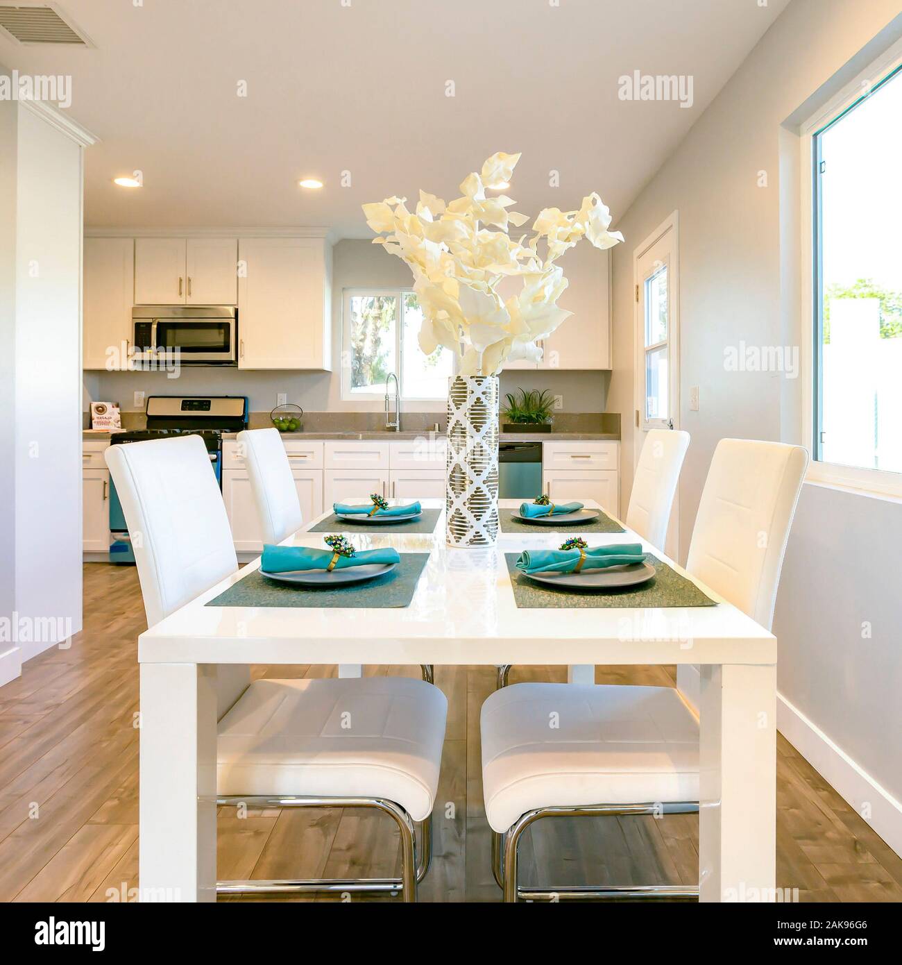 Square Kitchen table with all chairs pushed in Stock Photo - Alamy