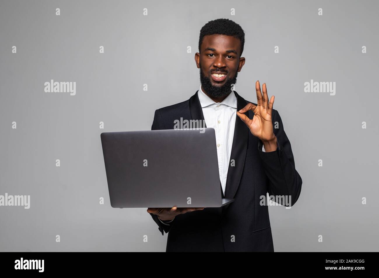 Serious African American businessman holding laptop computer on white ...