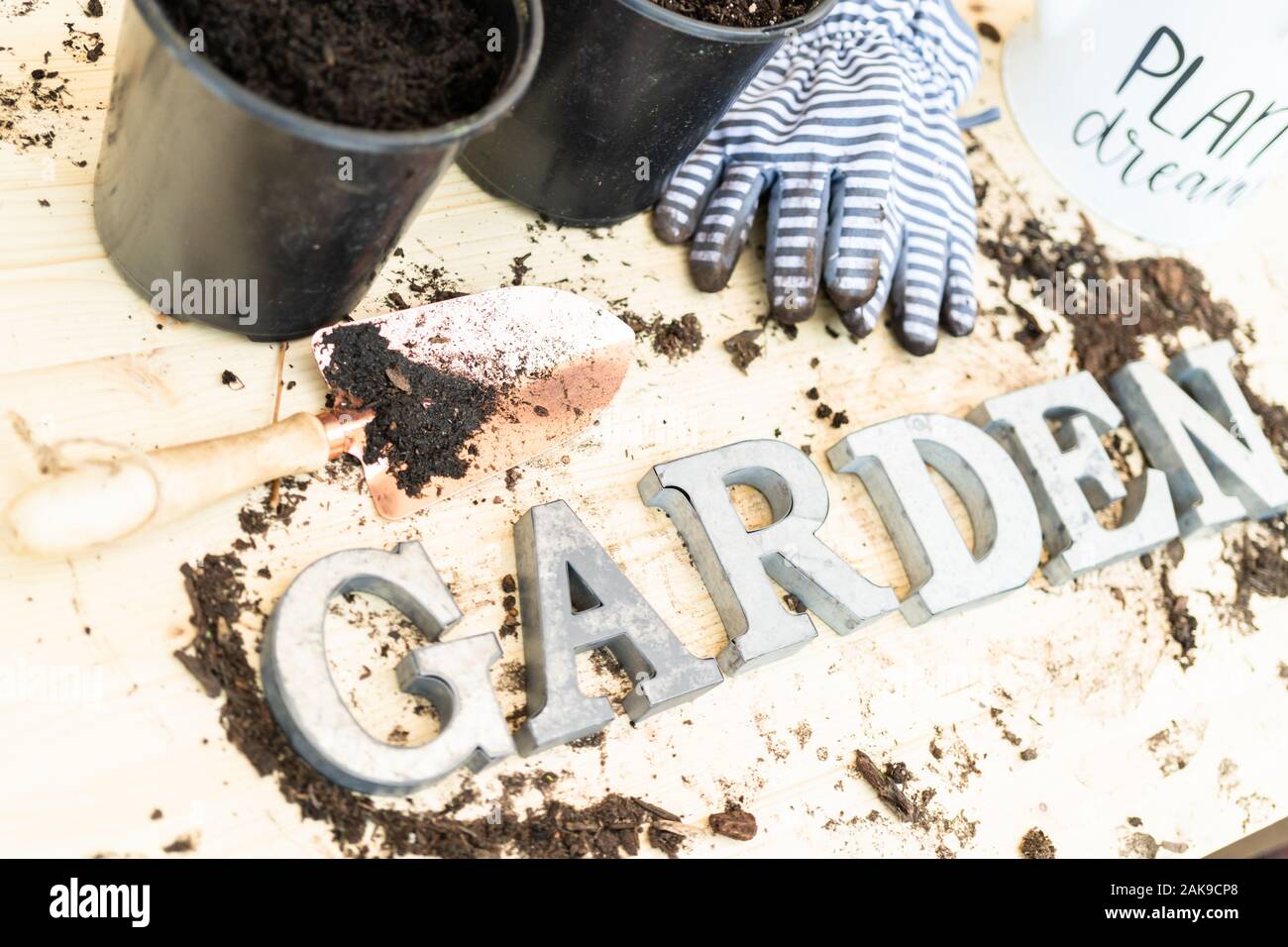 Sign GARDEN in metal letters around spilled soil and planting pots on a ...