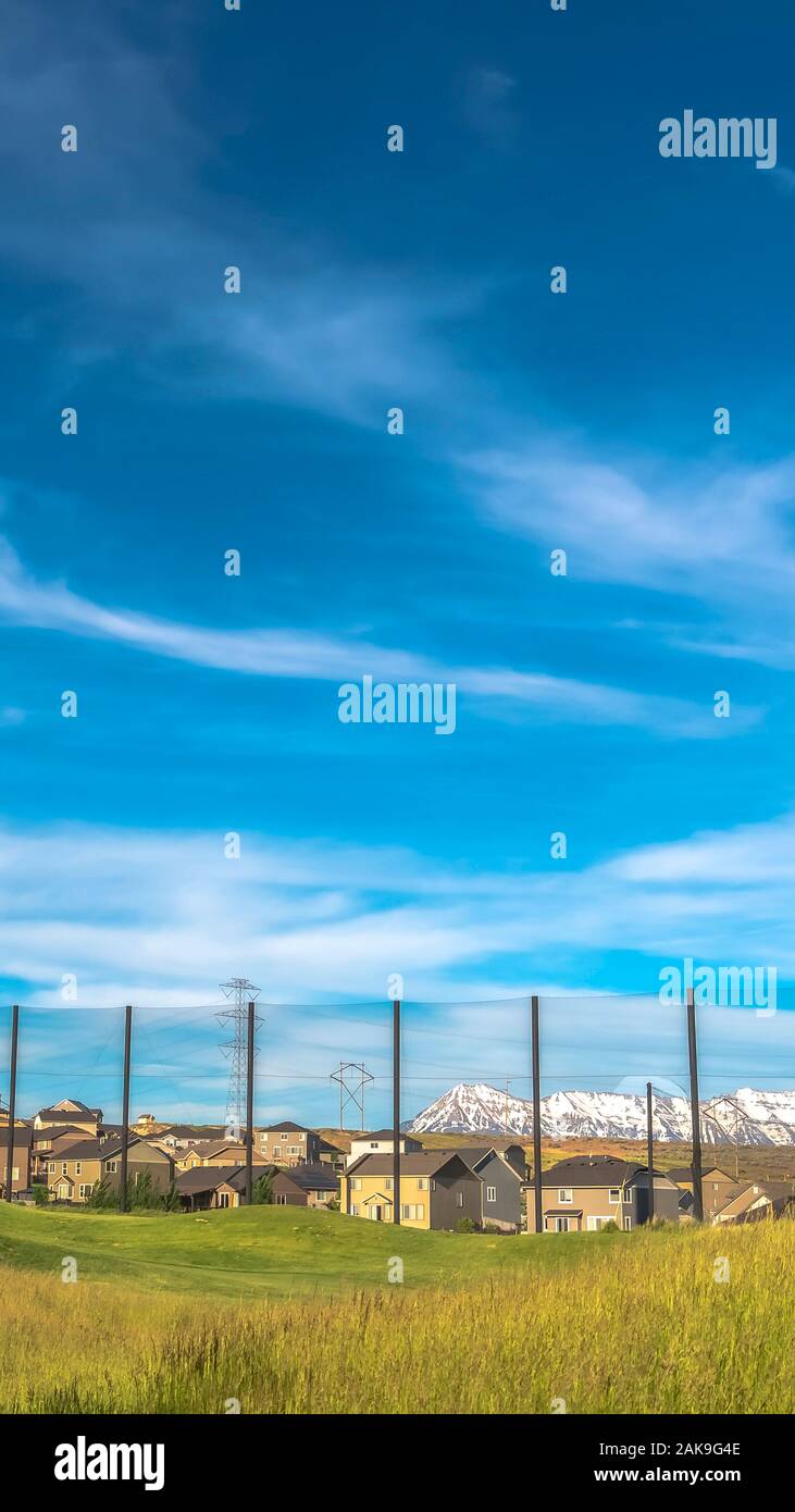 Vertical Golf course fence with homes and snow capped mountain in the ...