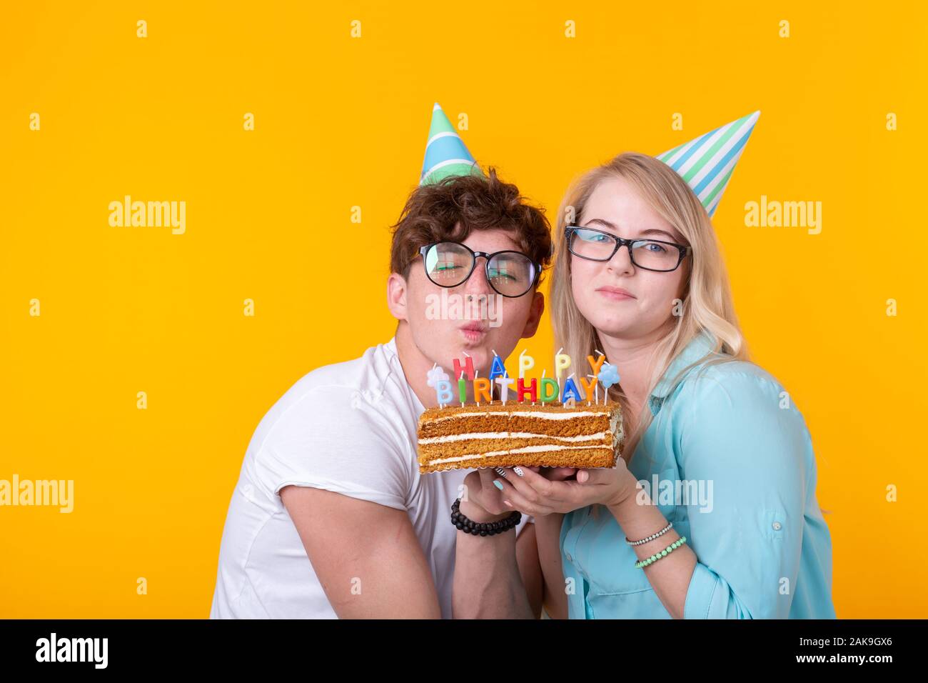 Cheerful young couple charming guy and cute girl in paper hats make ...