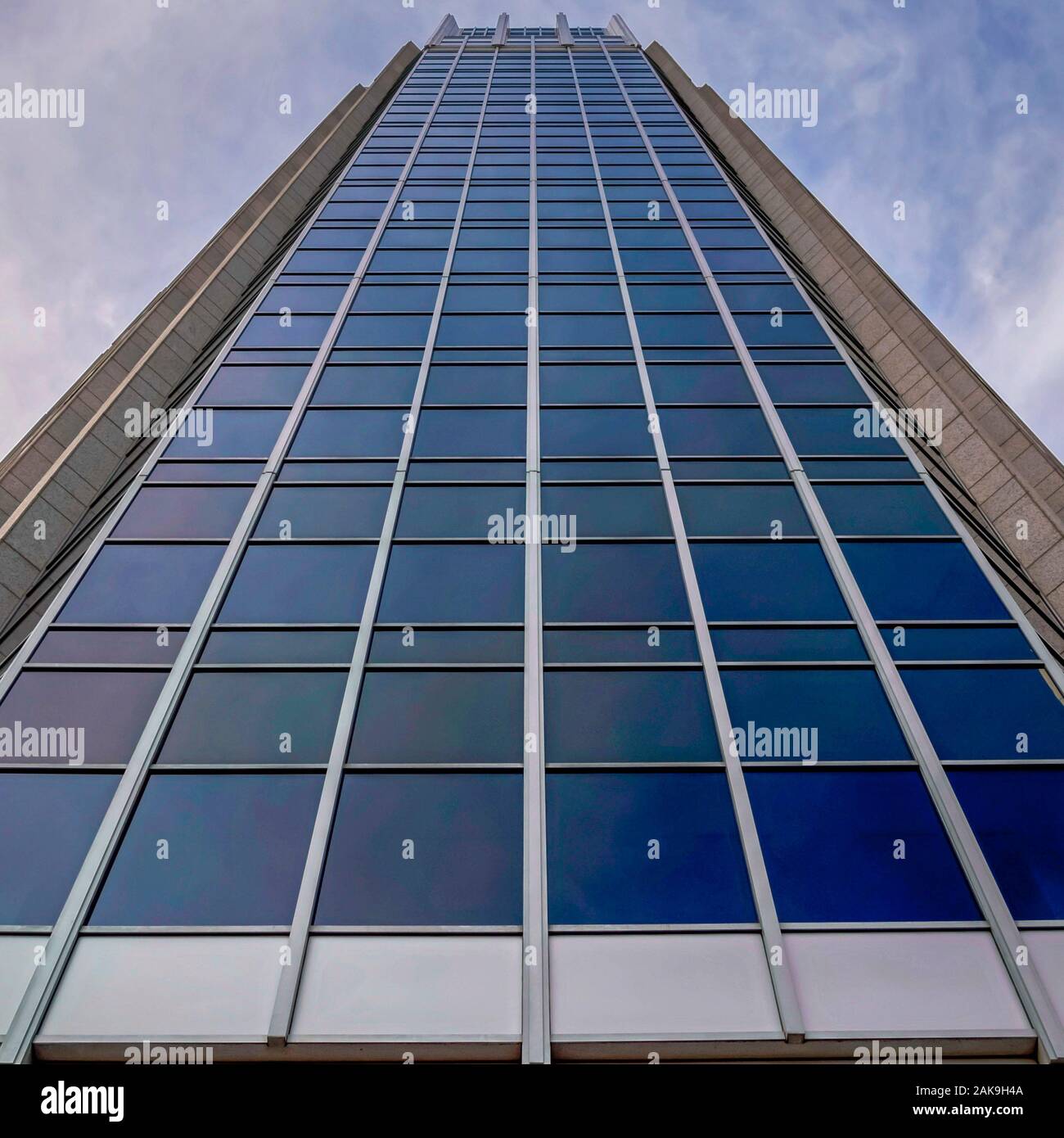 Square Modern building exterior viewed from below against white clouds ...