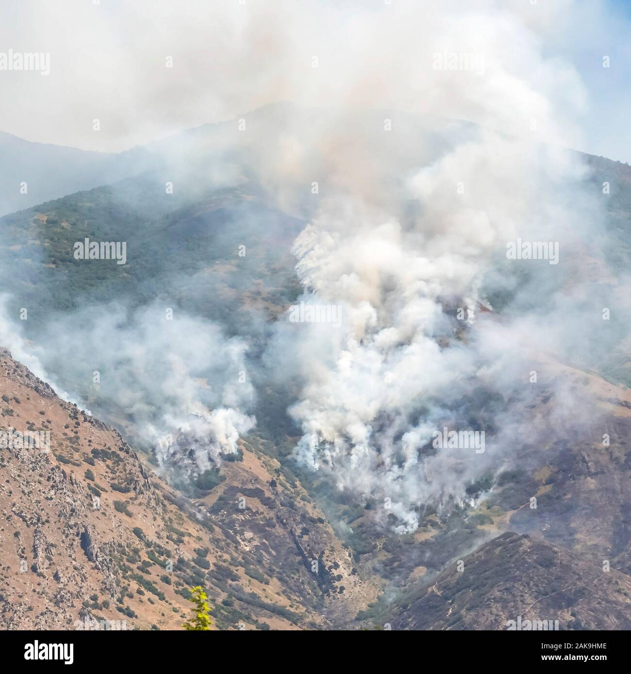 Square Nature landscape with puffs of white smoke rising from mountain ...