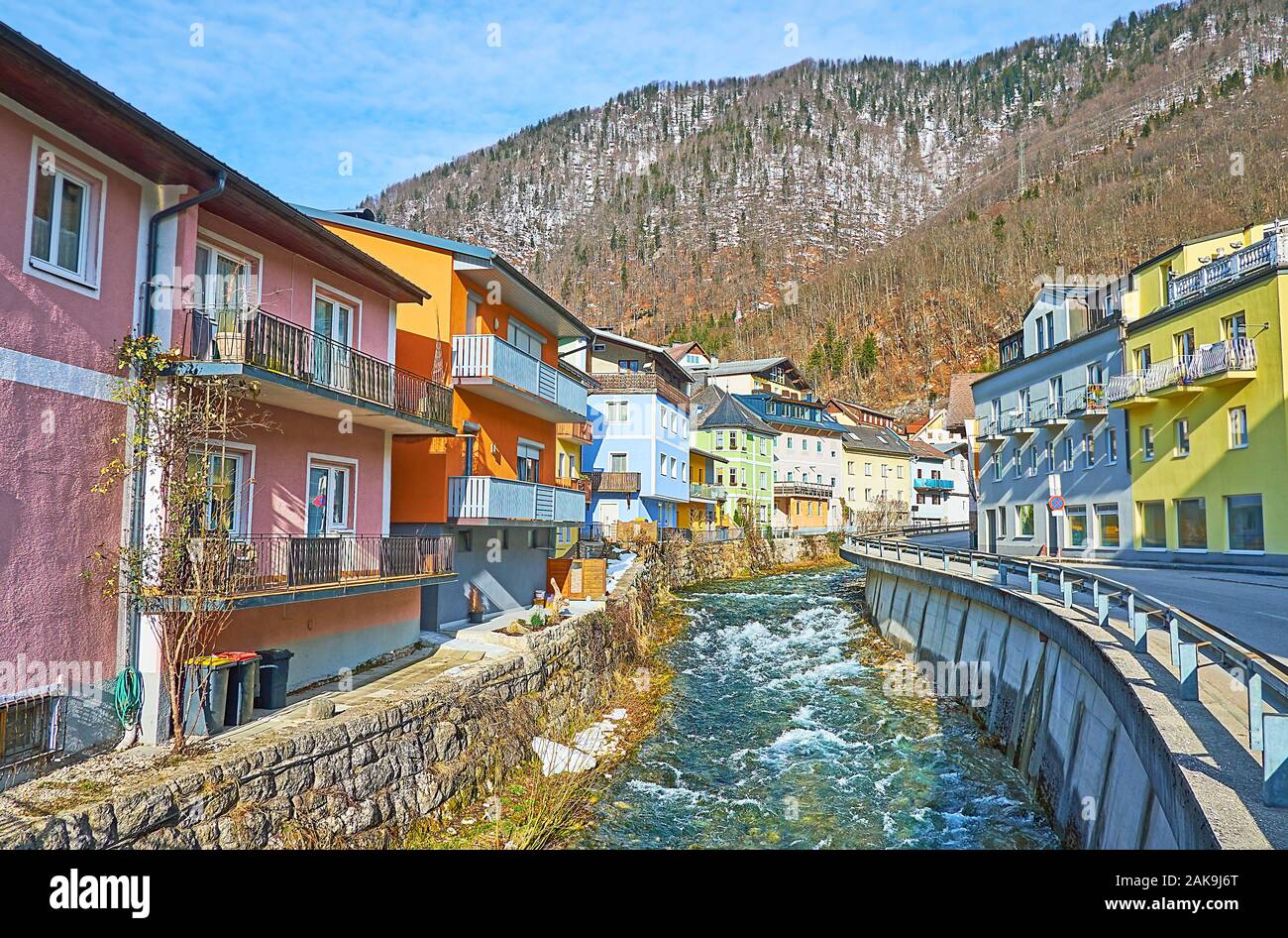 The narrow fast flowing Traun river, surrounded by colorful cottages of ...