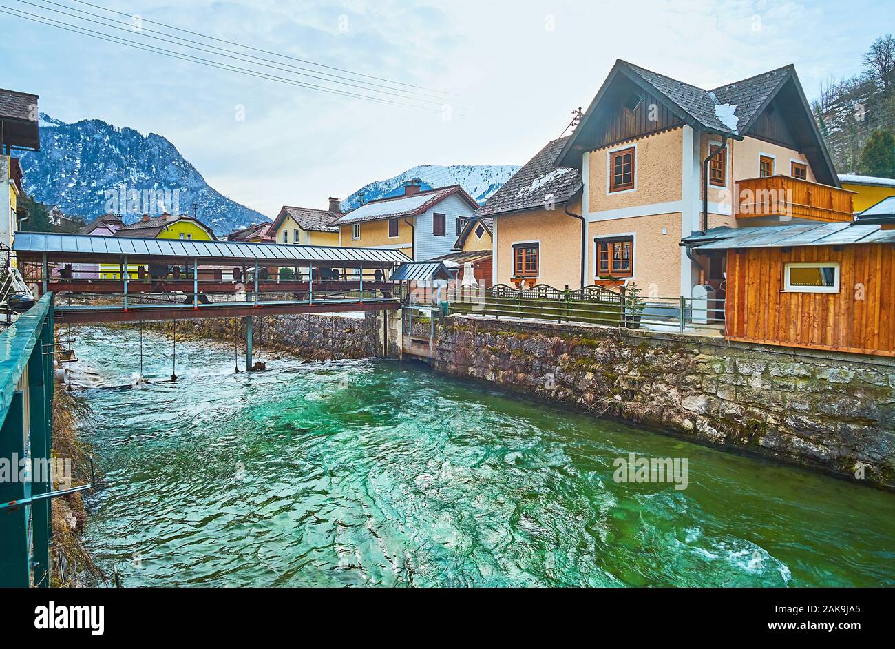 The dam on mountain Traun river, with line of old houses on its bank ...