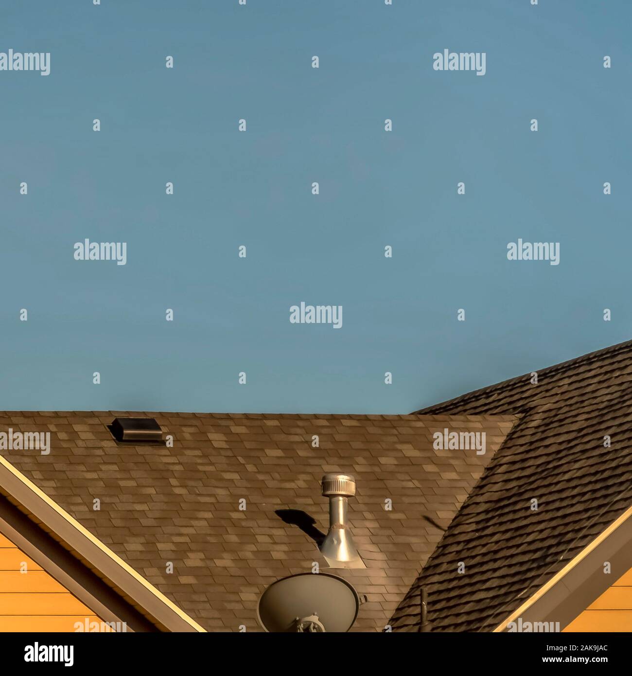 Square House exterior with roof shingles and round gable window against ...