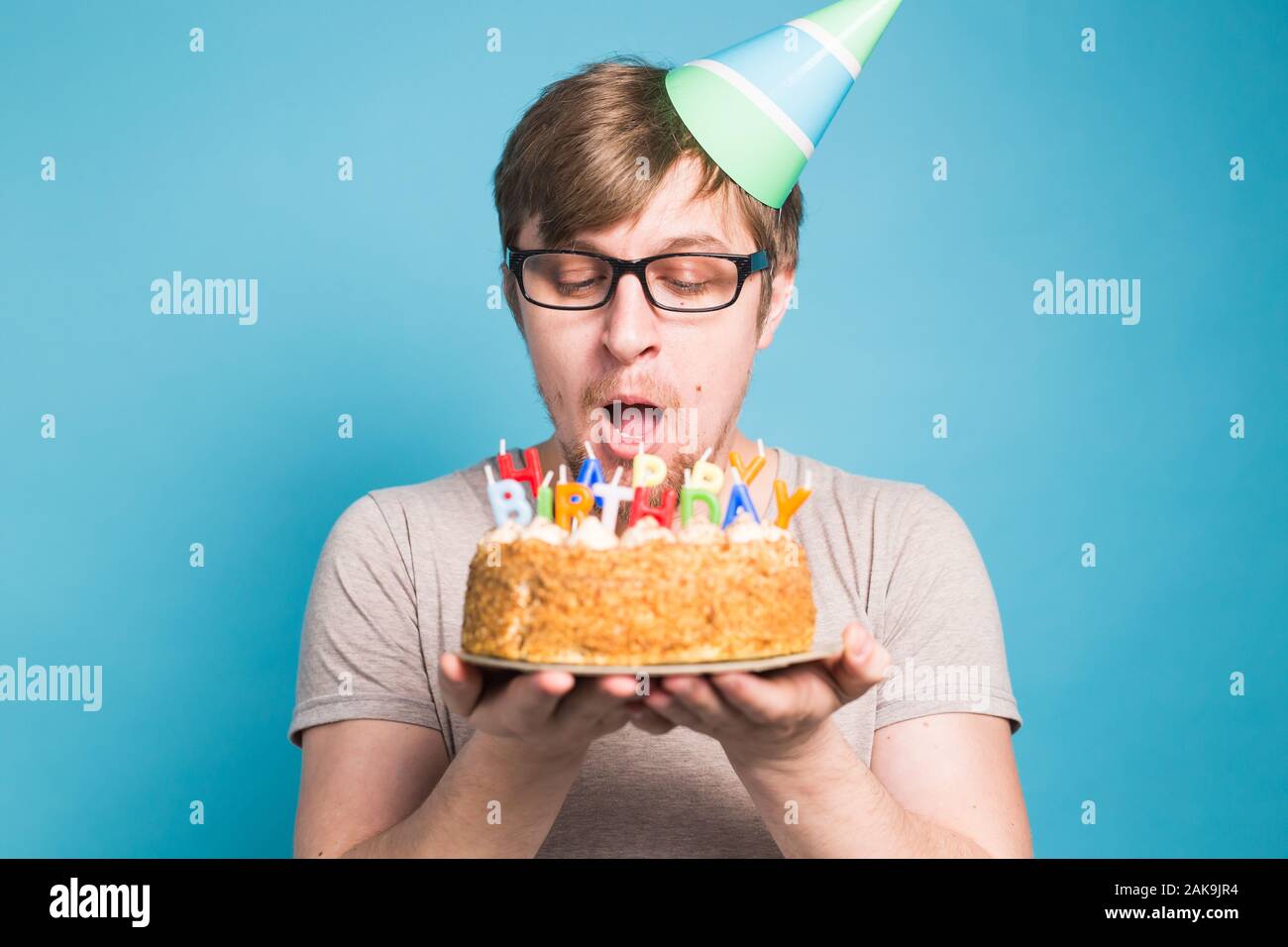 Crazy cheerful young man in glasses and paper congratulatory hats ...