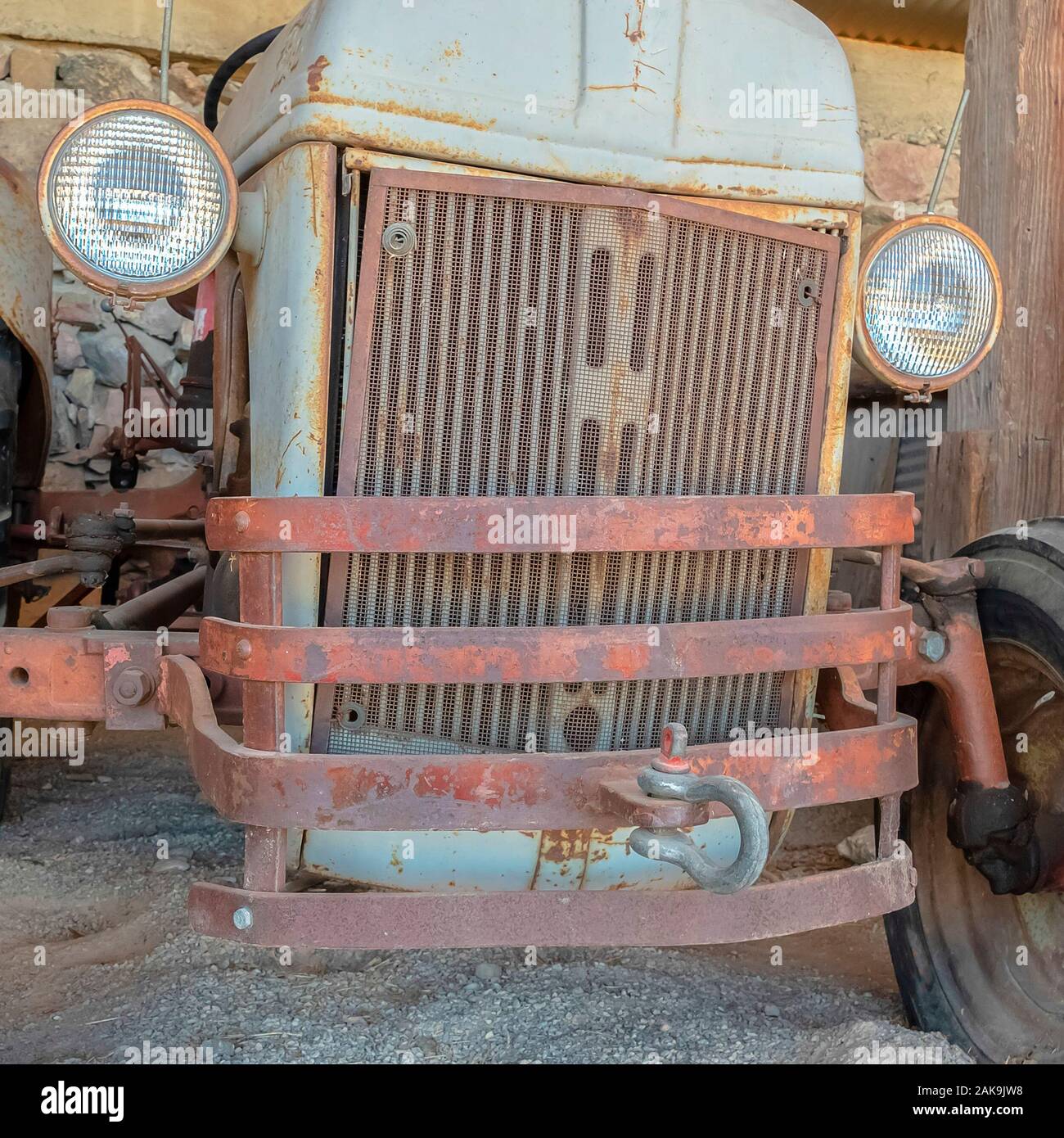 Square frame Front of an old and vintage tractor against stone wall and ...