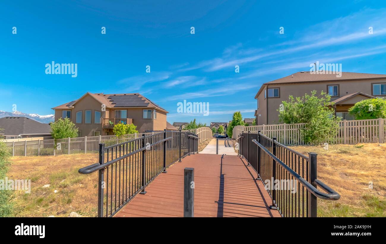 Pano Bridge over a grassy terrain with homes mountain and blue sky ...