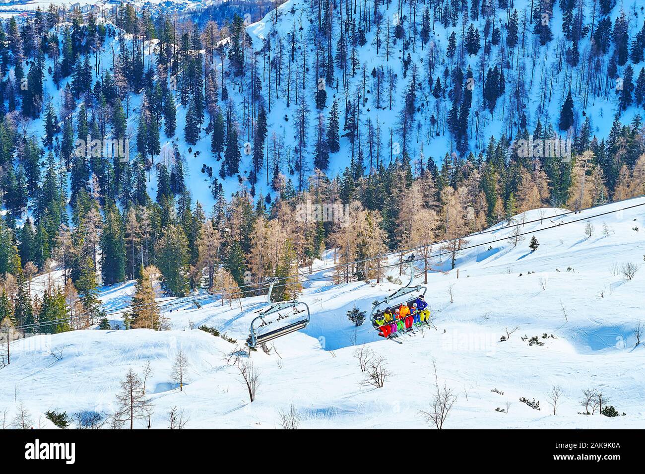 The ski lift cabins, carrying people along the white snowy slope of ...
