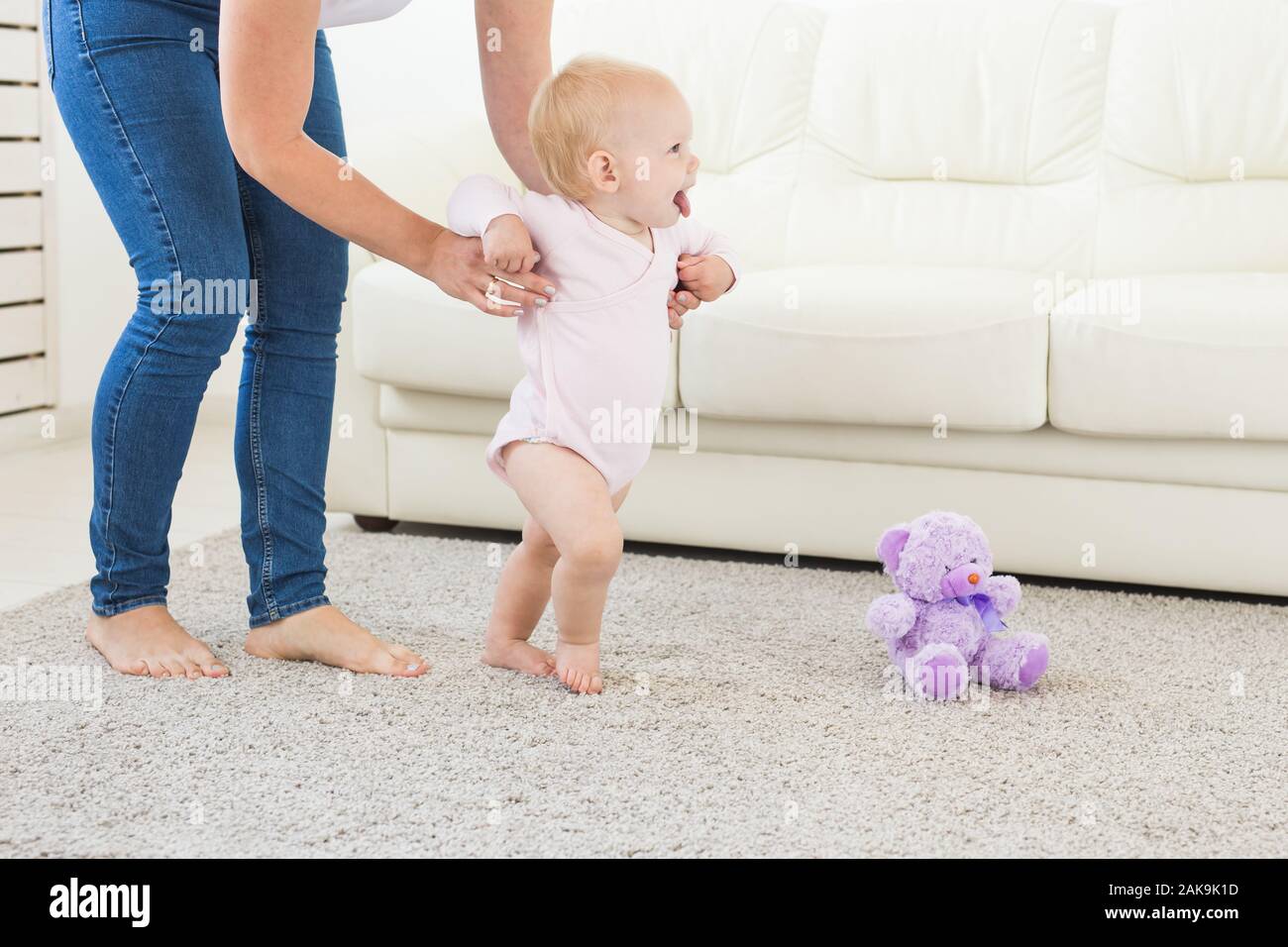 Baby taking first steps with mother's help at home Stock Photo - Alamy