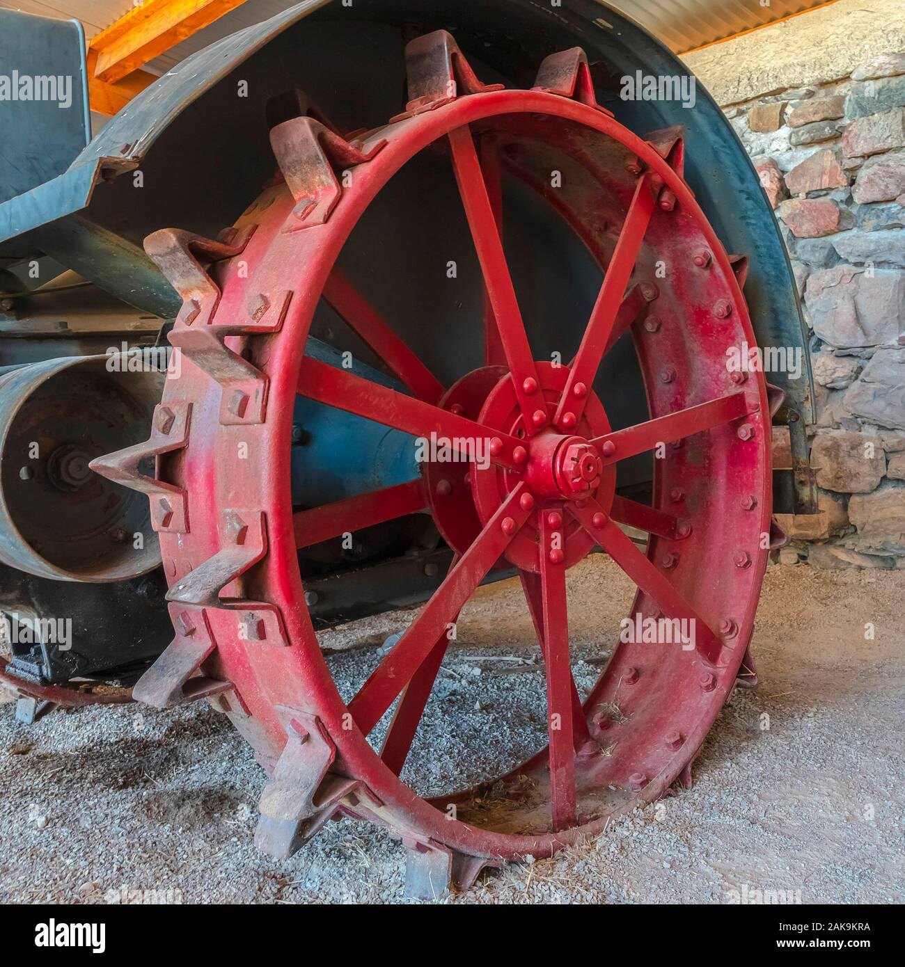 Square Red wheel rim of an and vintage tractor against stone wall of a ...