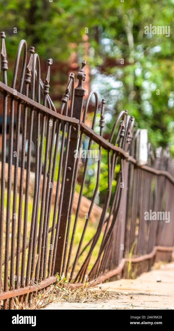 Vertical Close up of old and rusty iron fence against grassy slope ...