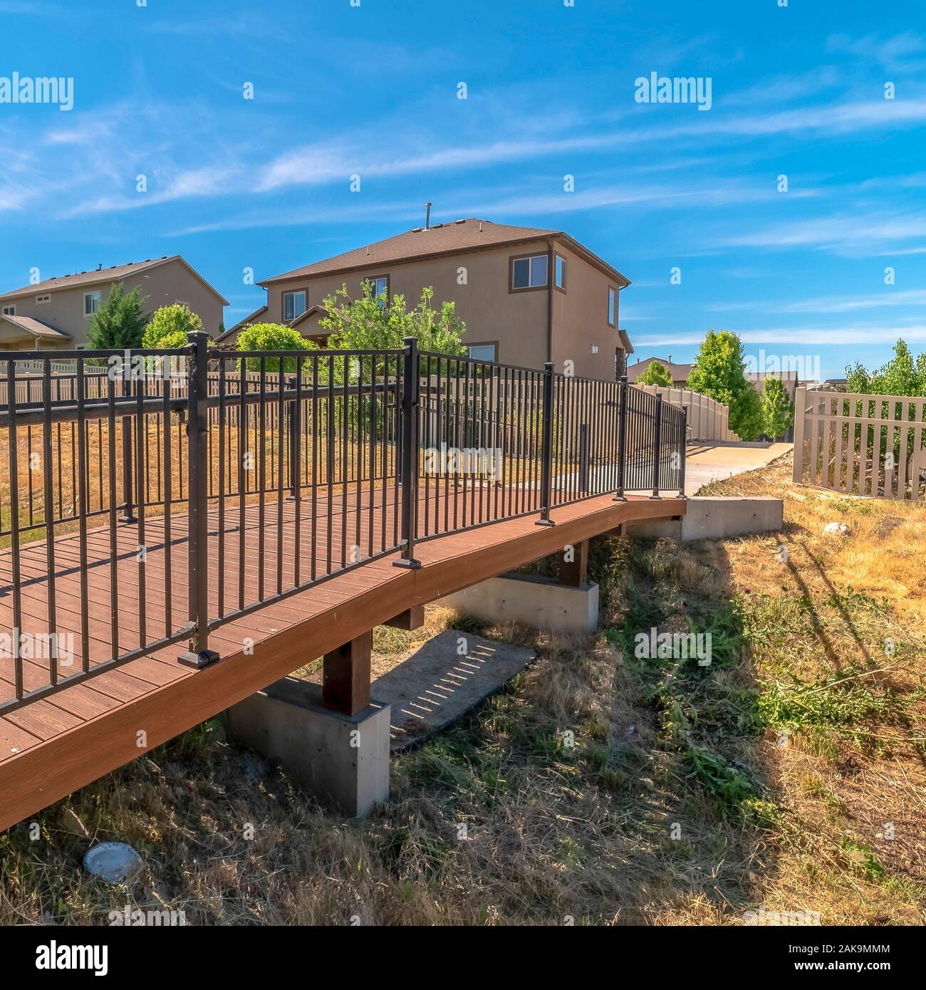 Square Side view of a bridge over a grassy terrain with homes and blue ...