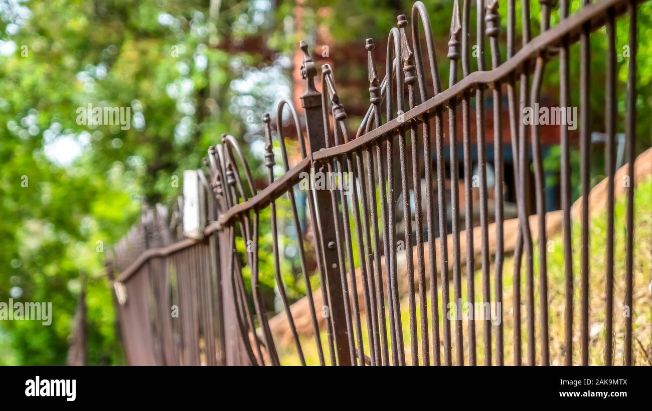 Pano frame Close up of old and rusty iron fence against grassy slope ...