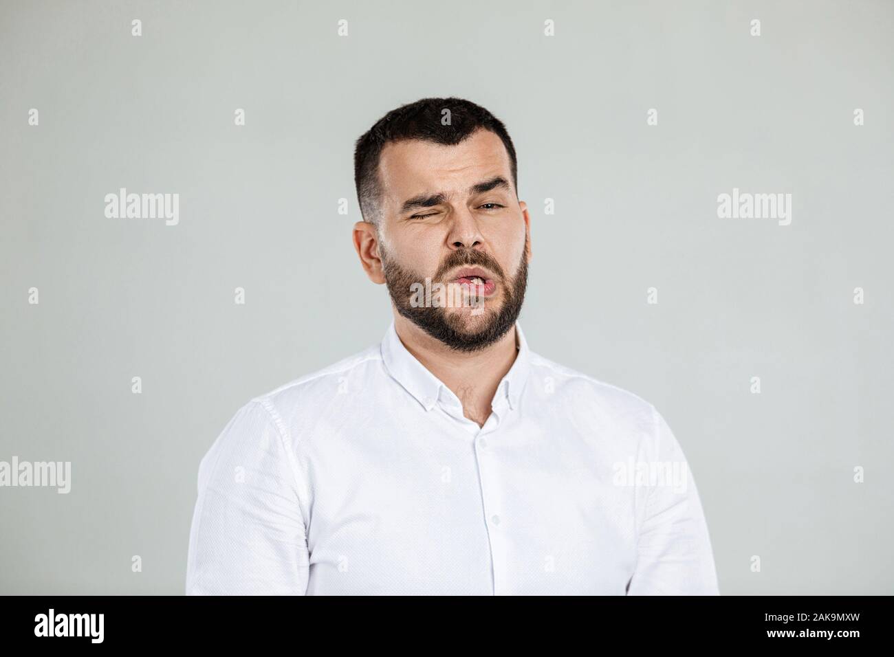 Portrait of young frowned handsome bearded man on gray background ...