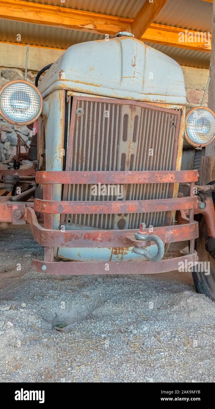 Vertical frame Front of an old and vintage tractor against stone wall ...