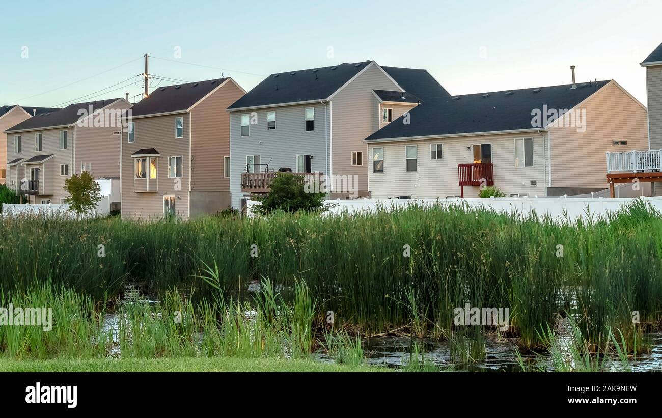 Pano frame Green grasses and pond at a scenic park with houses and blue ...