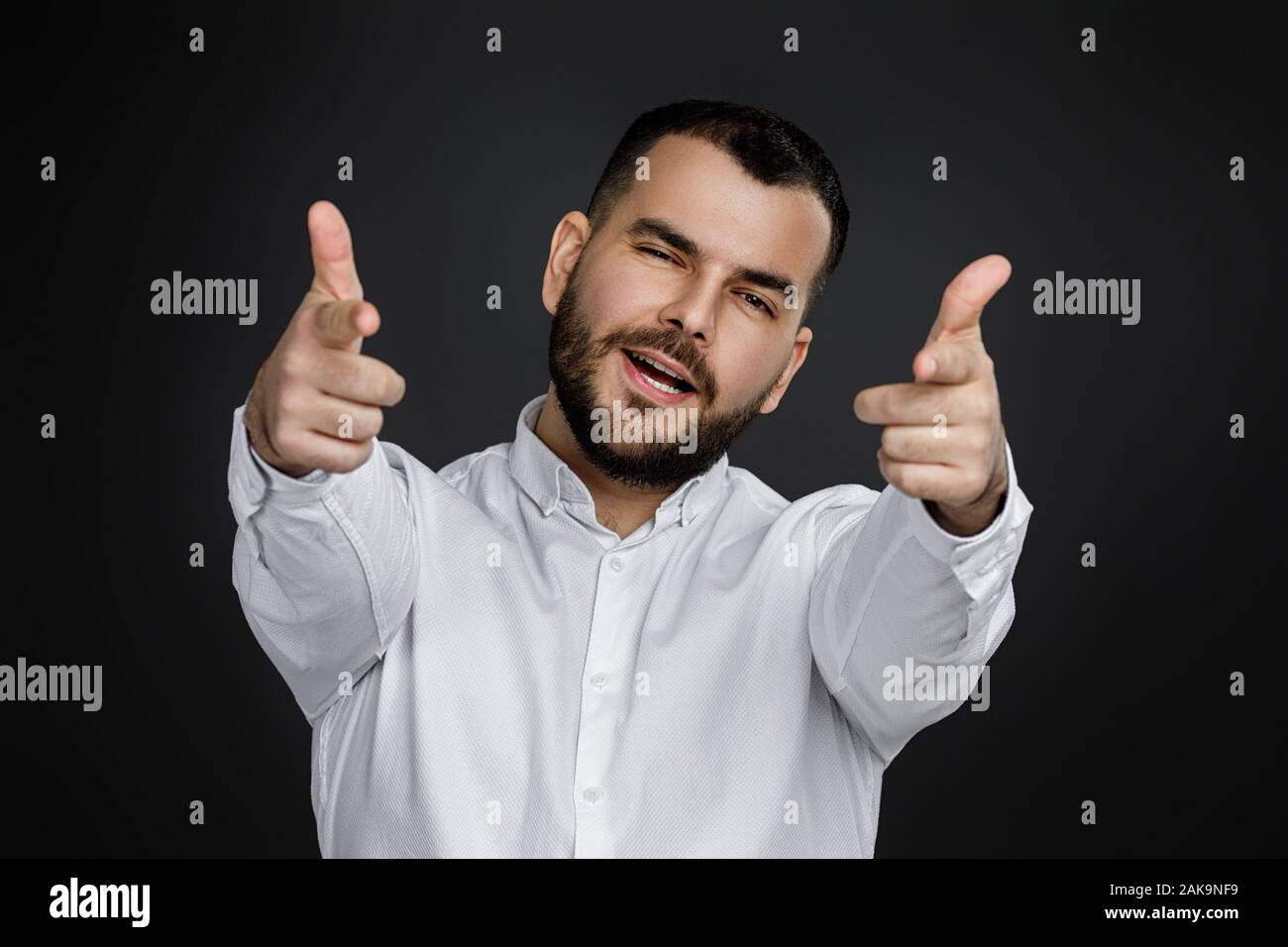 handsome smiling young man points hand at you on black background. man ...