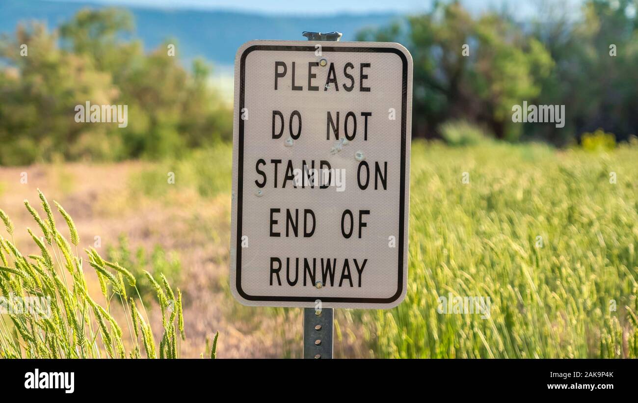Pano frame Road sign with grasses trees mountain and cloudy sky in the ...