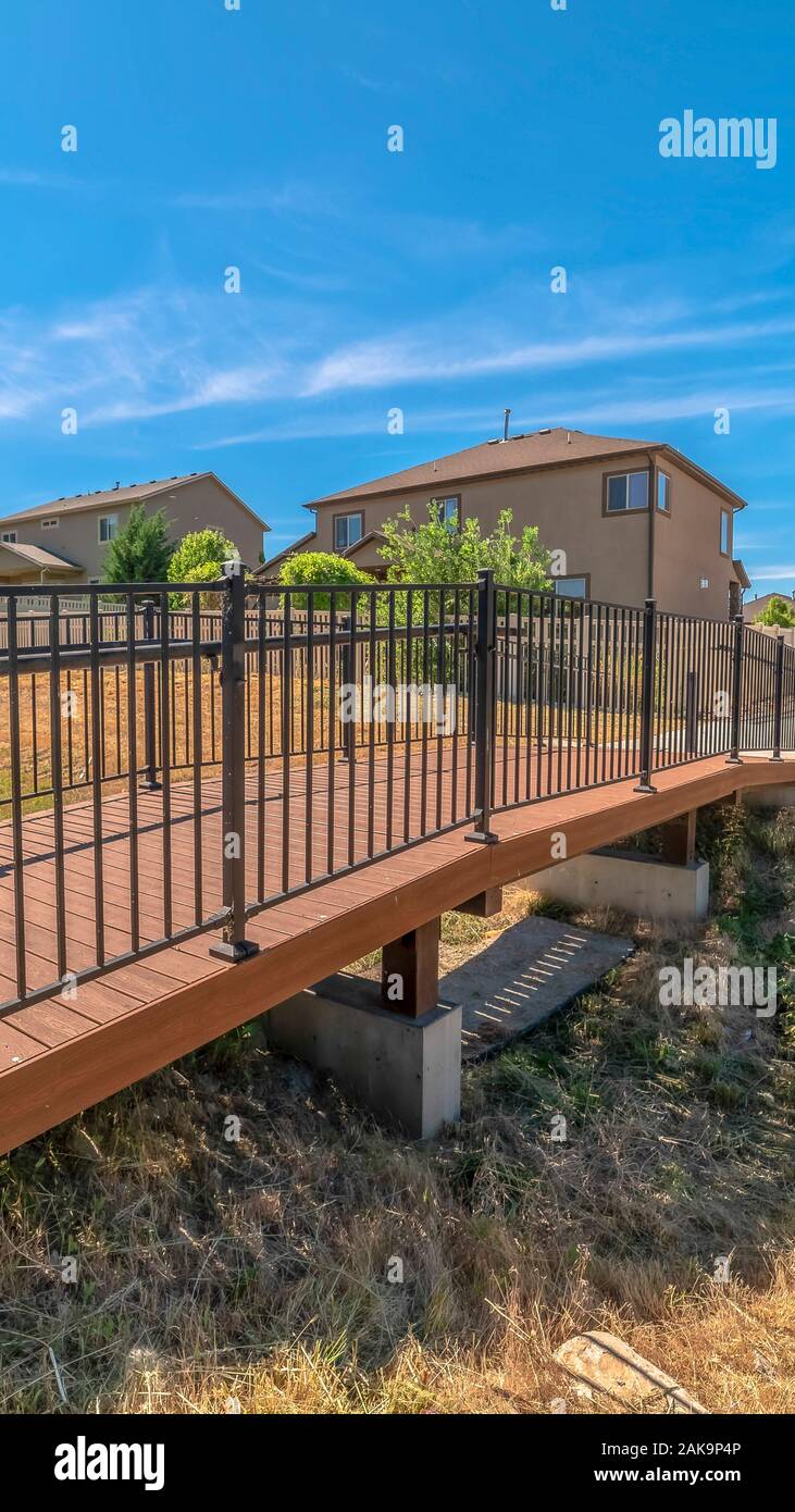Vertical frame Side view of a bridge over a grassy terrain with homes ...