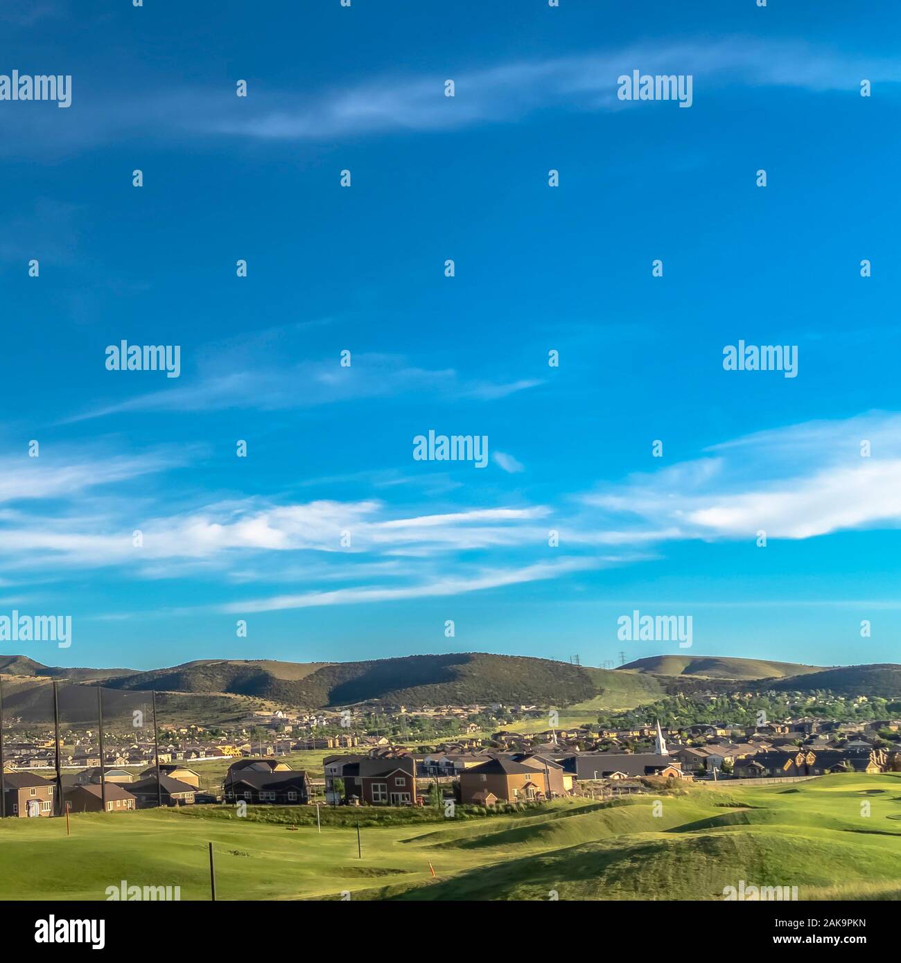 Square Golf course fairway and putting green with flagsticks under blue ...