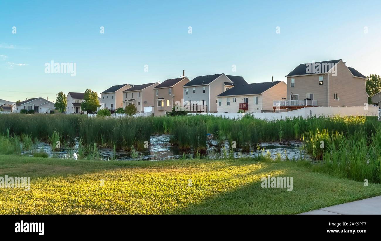 Pano frame Pathway and bridge over pond at a park with lush grasses ...